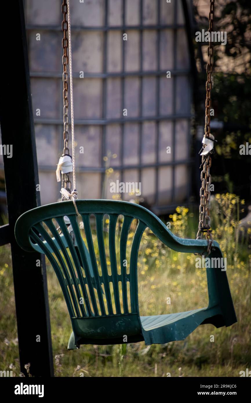 A rustic swing composed of a deconstructed chair and chains suspended ...