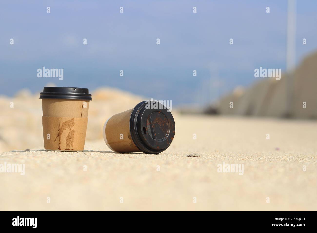 Disposable cardboard cup with plastic lid thrown on floor. Dirty coffee ...