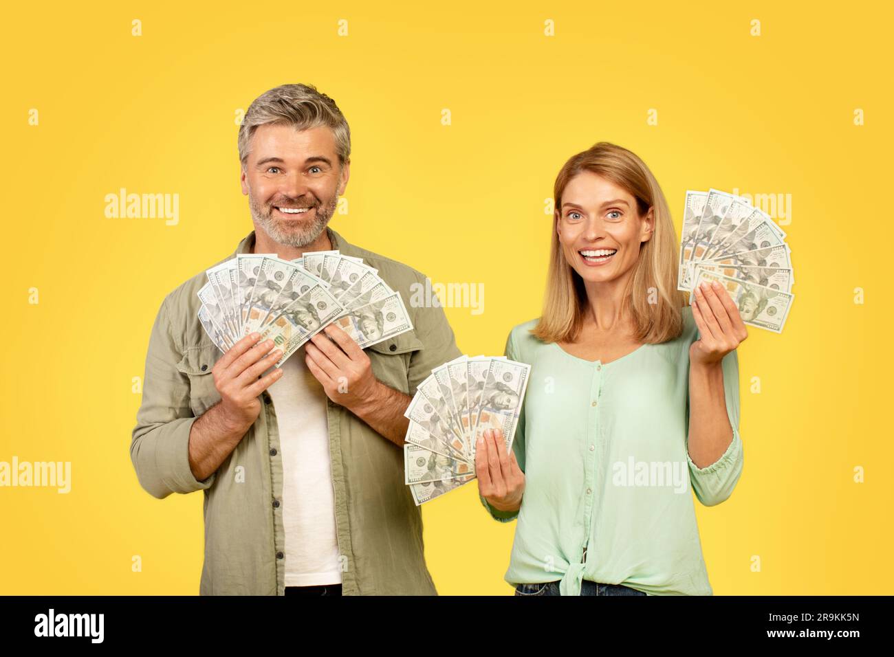 Family savings concept. Happy middle aged couple standing over yellow ...