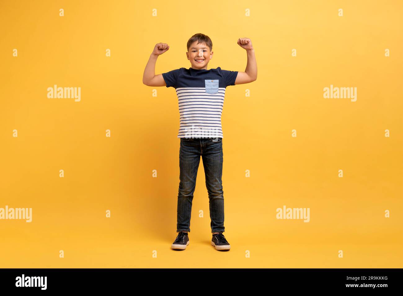 Strong cute kid boy showing muscles, yellow background Stock Photo - Alamy