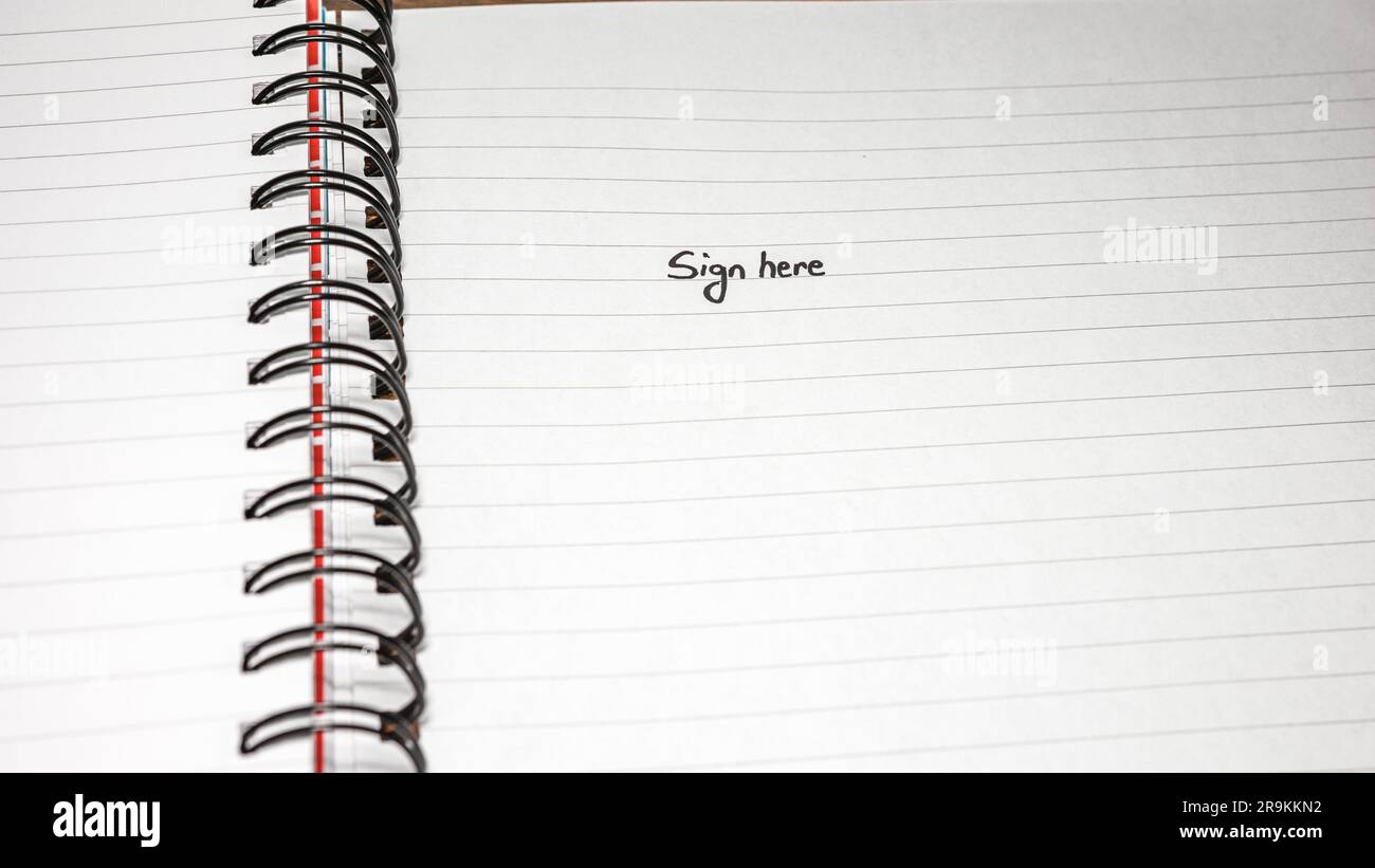 Sign here, handwriting text on page of office agenda, office spiral ...