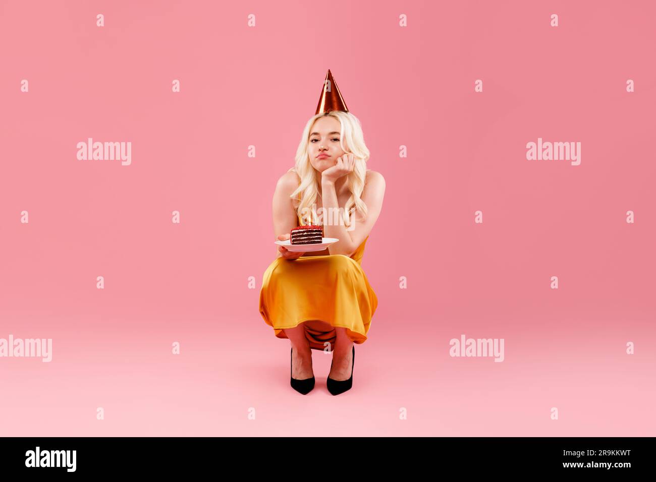 Sad young woman in party hat holding birthday cake, feeling lonely on ...