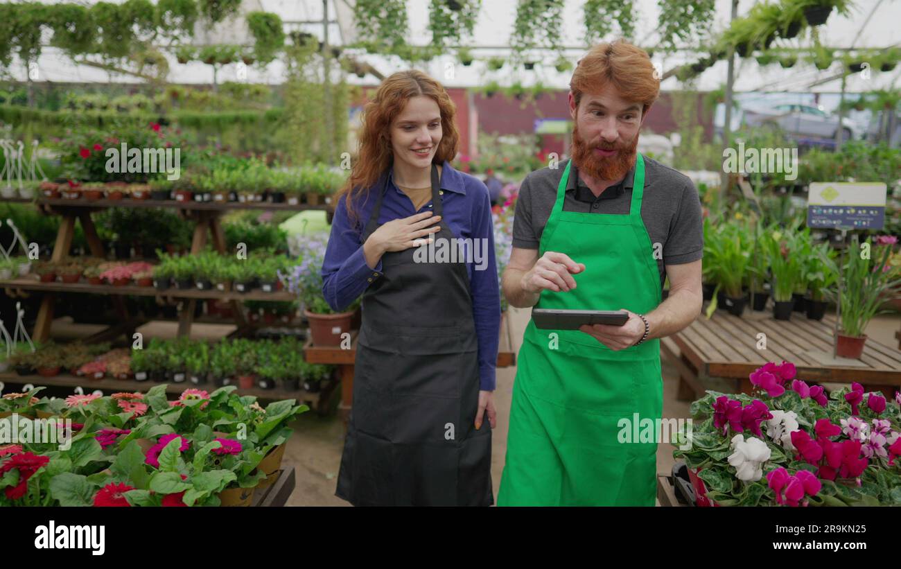 A male employee showing inventory to female colleague walking inside ...