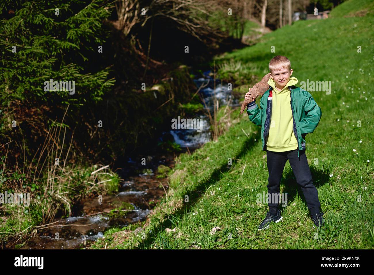 A little boy walks along a mountain river. Through the clear water, he ...