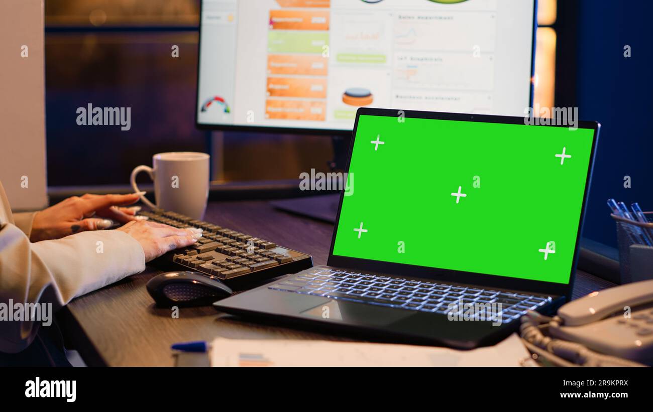 Executive agent analyzing green screen on laptop, sitting at desk ...