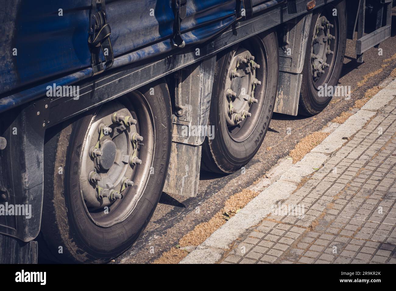 An aged blue and grey truck is shown with three tires on the side Stock ...