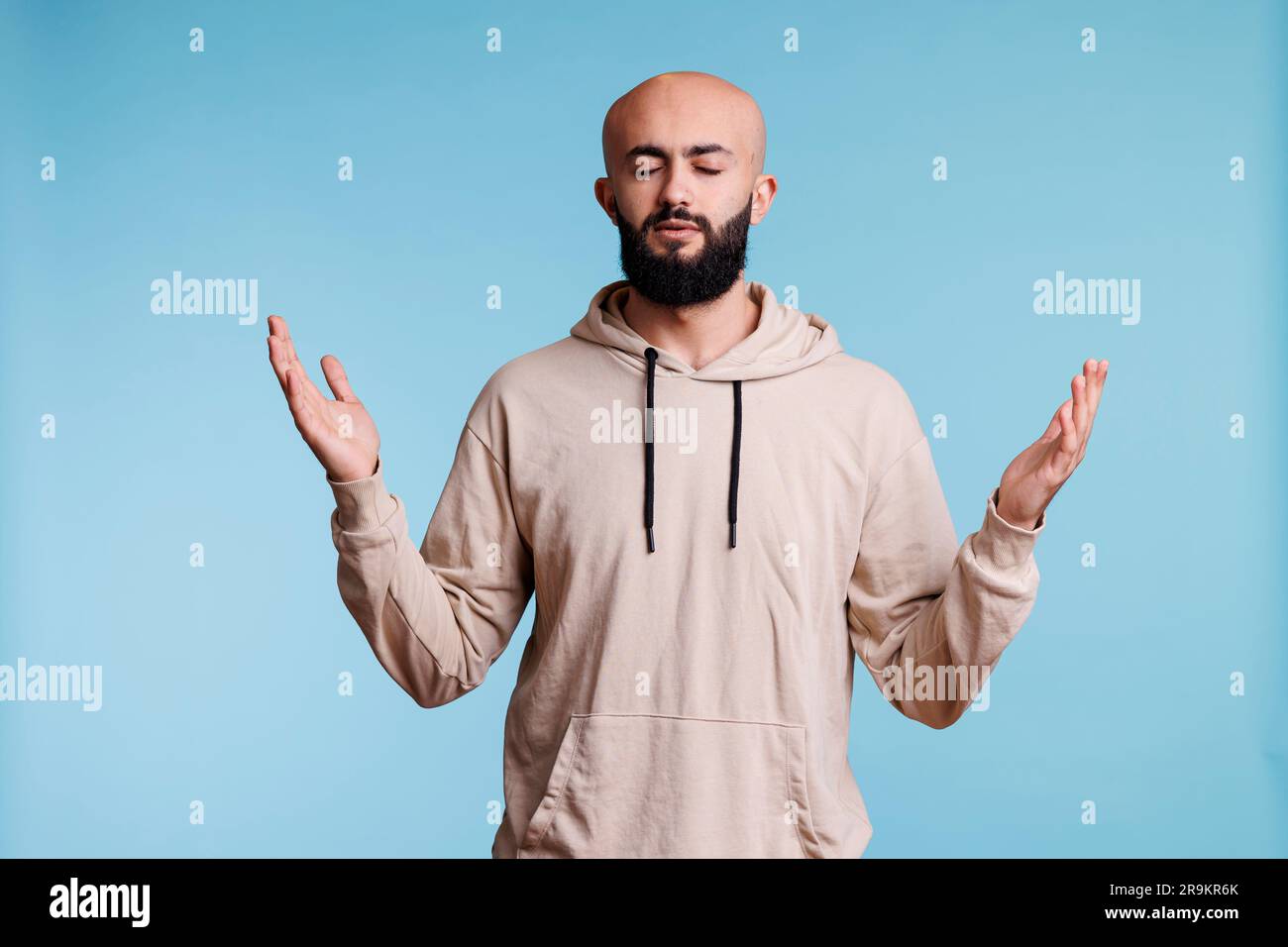 Arab man praying and making worship gesture with open arms and closed ...