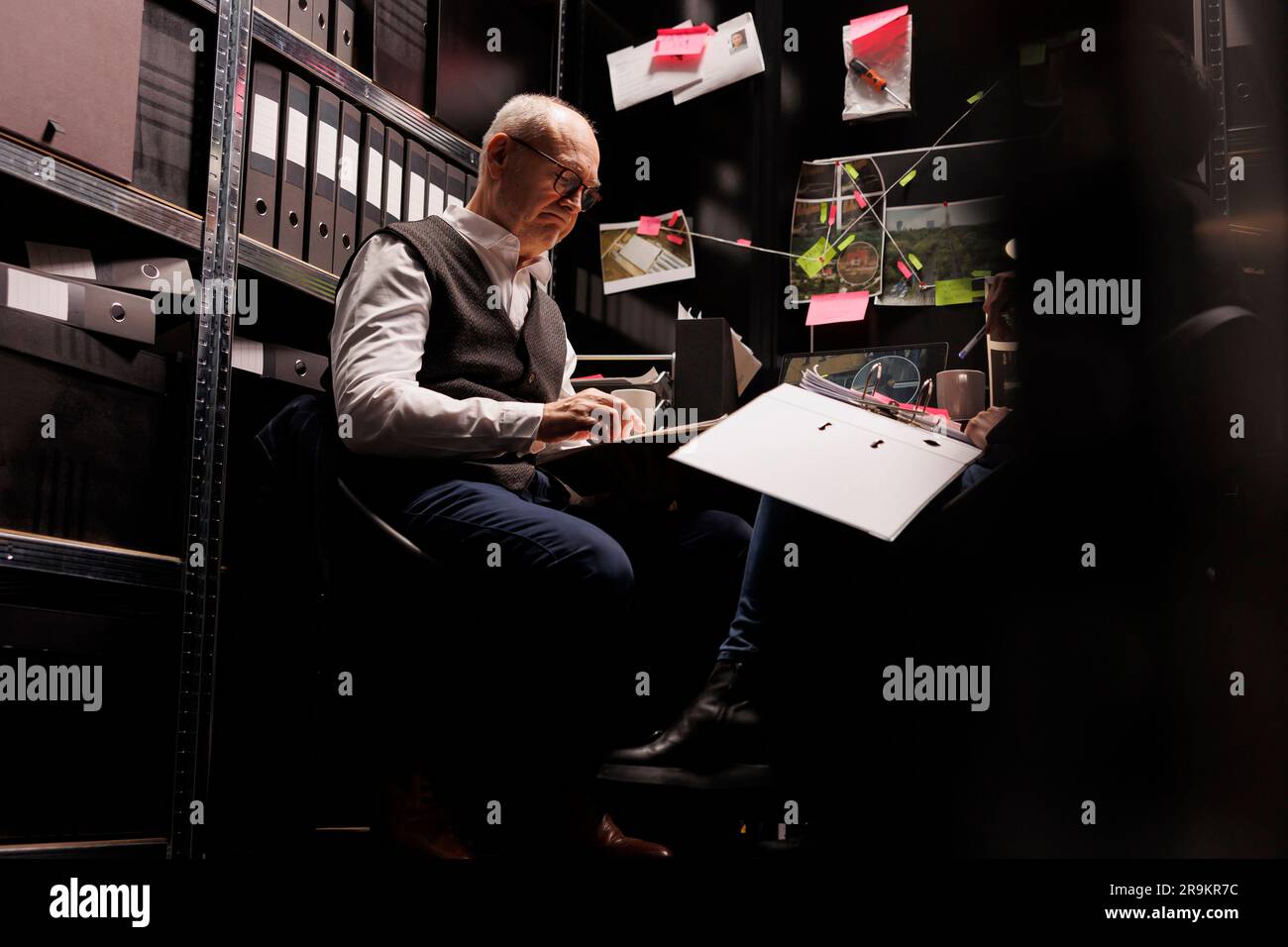 Elderly investigator analyzing missing person report, working late at ...