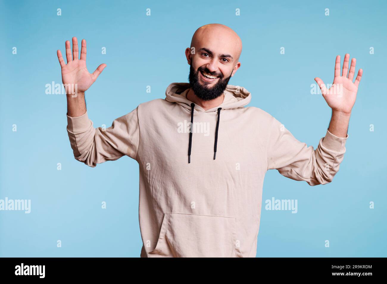 Smiling arab man with cheerful facial expression raising hands studio ...