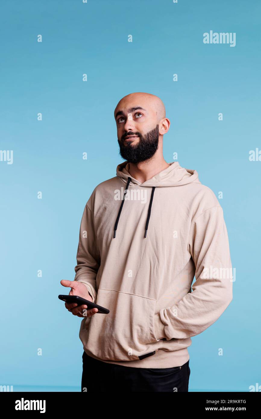 Arab man using smartphone, thinking while typing online message and ...