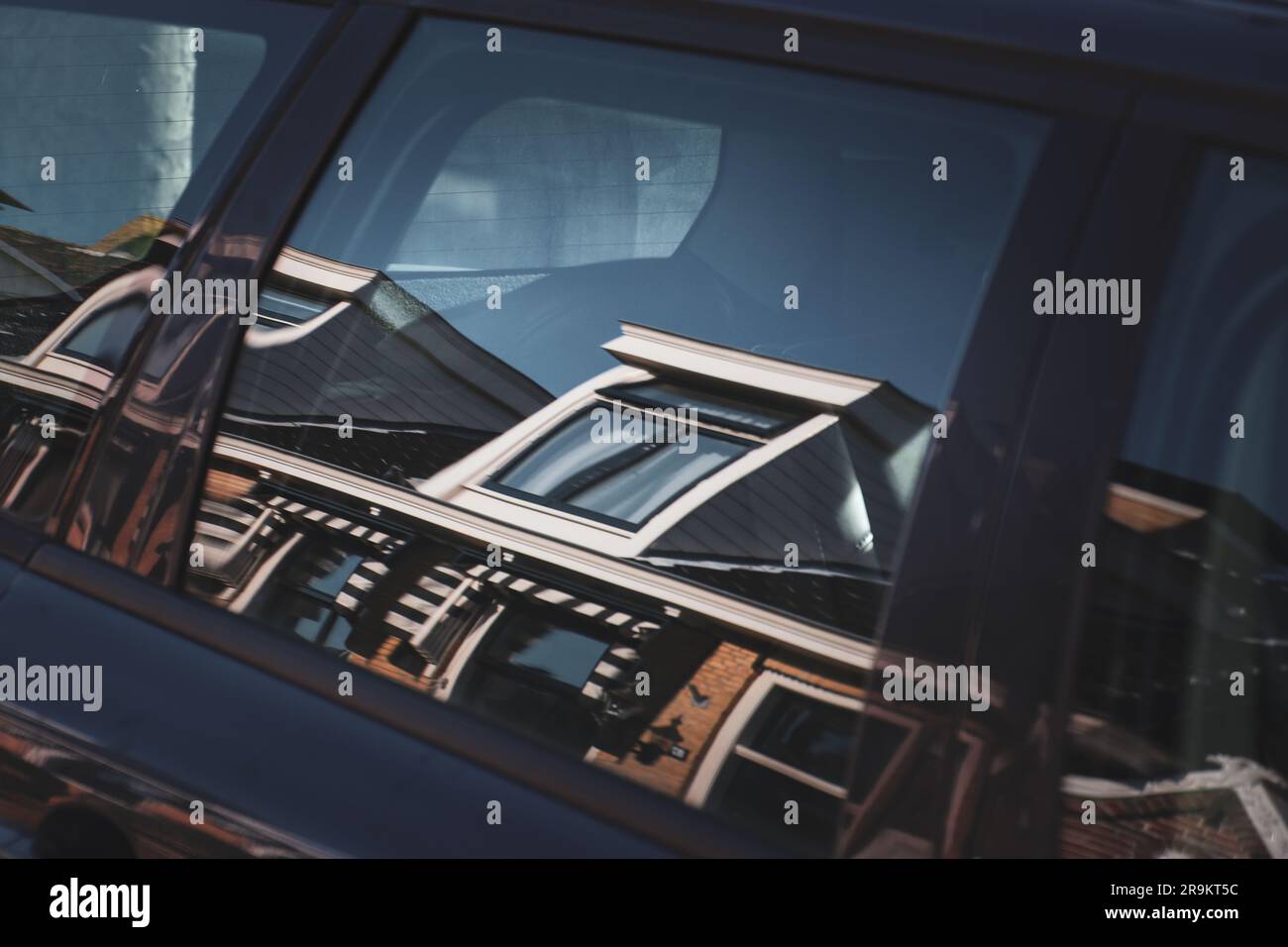 A light blue minivan is parked in front of a large two-story house with ...