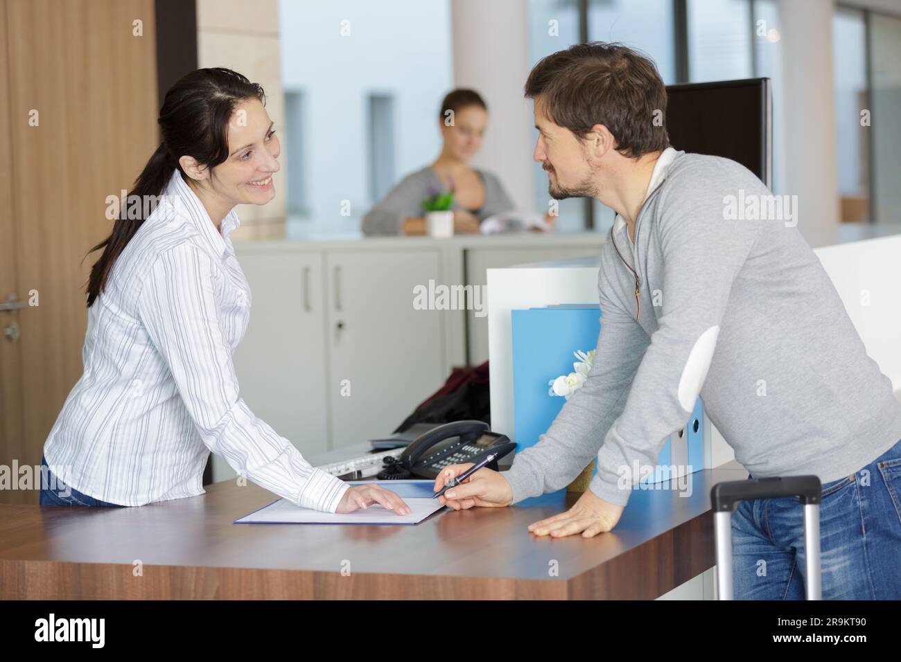 man signing in at reception desk Stock Photo - Alamy