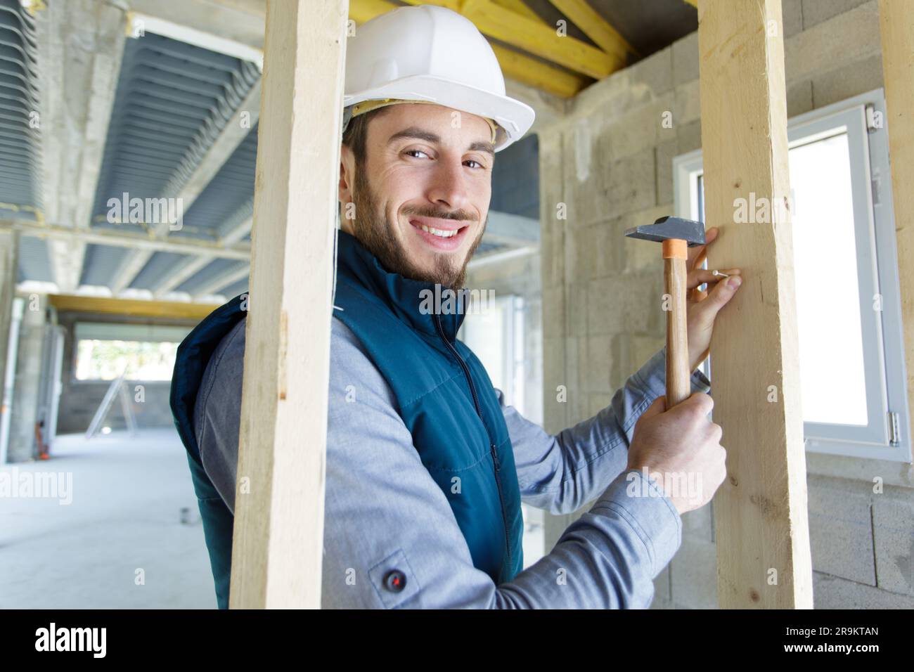 happy builder hammers a nail into a wooden beam Stock Photo - Alamy