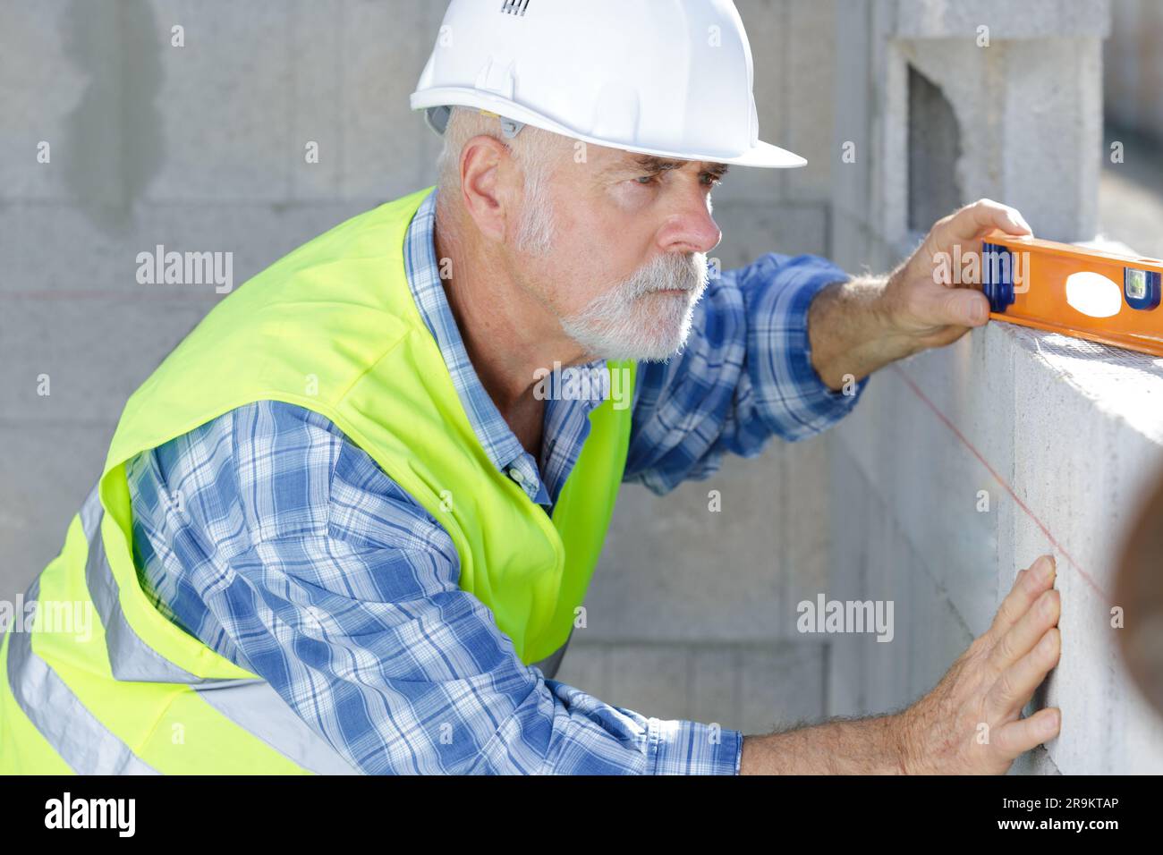 builder holding angled spirit level to wall Stock Photo - Alamy