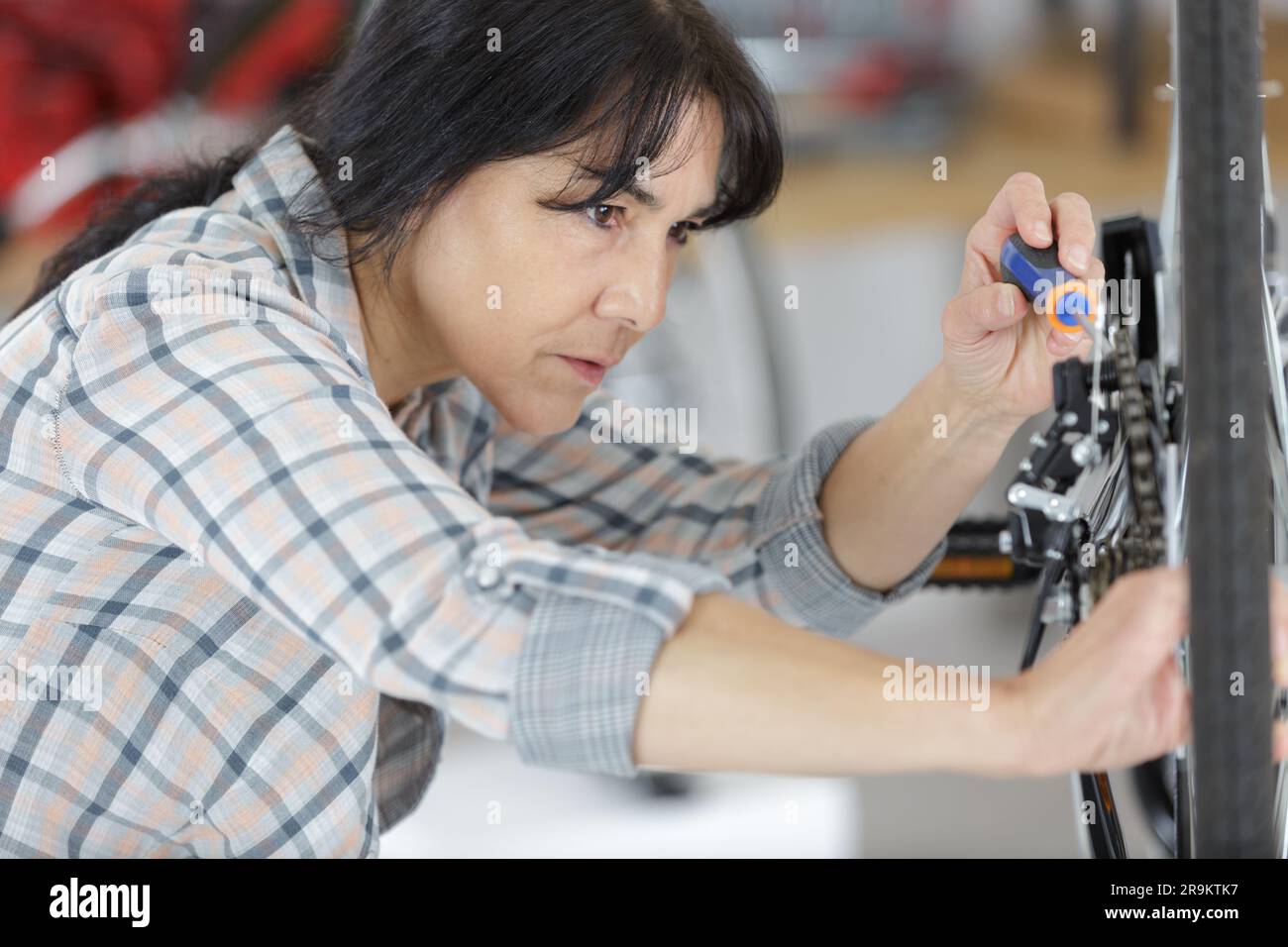 female bicycle mechanic repairing bicycle wheel in courtyard Stock ...