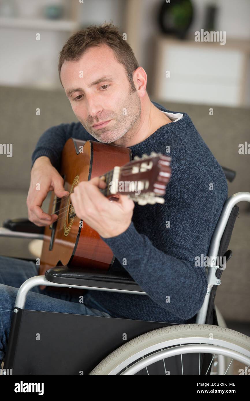 musician in wheelchair playing guitar at home Stock Photo - Alamy