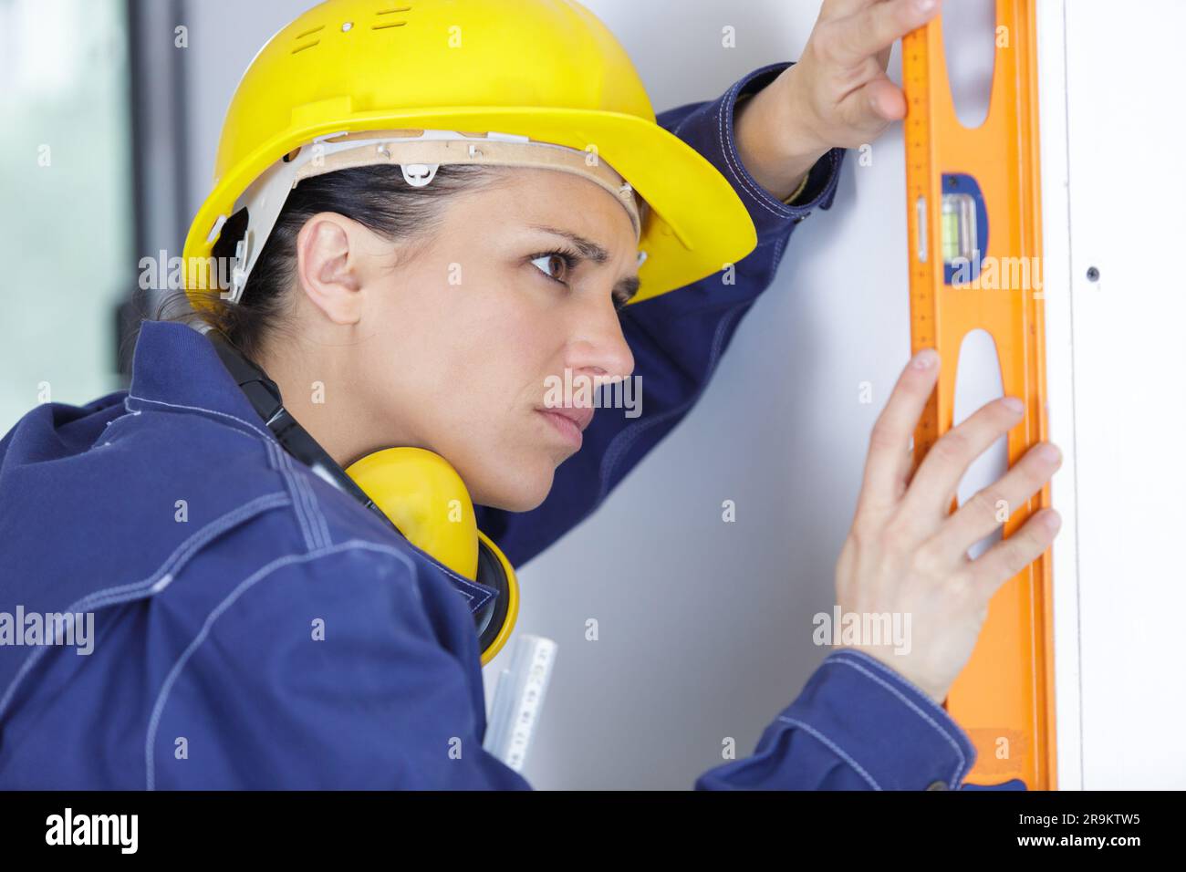 focused female worker using a spirit level Stock Photo - Alamy