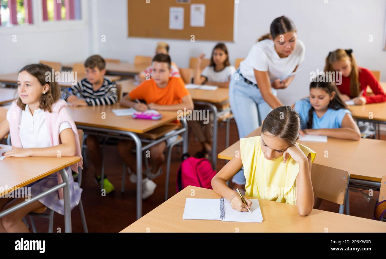 School kids with pens and notebooks studying in classroom with teacher ...