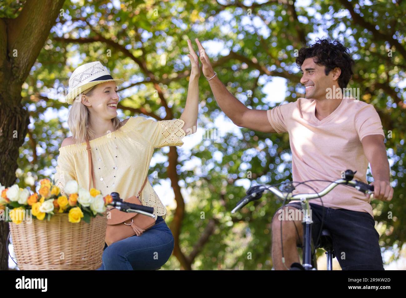 cyclist couple giving high five while riding bicycles Stock Photo - Alamy