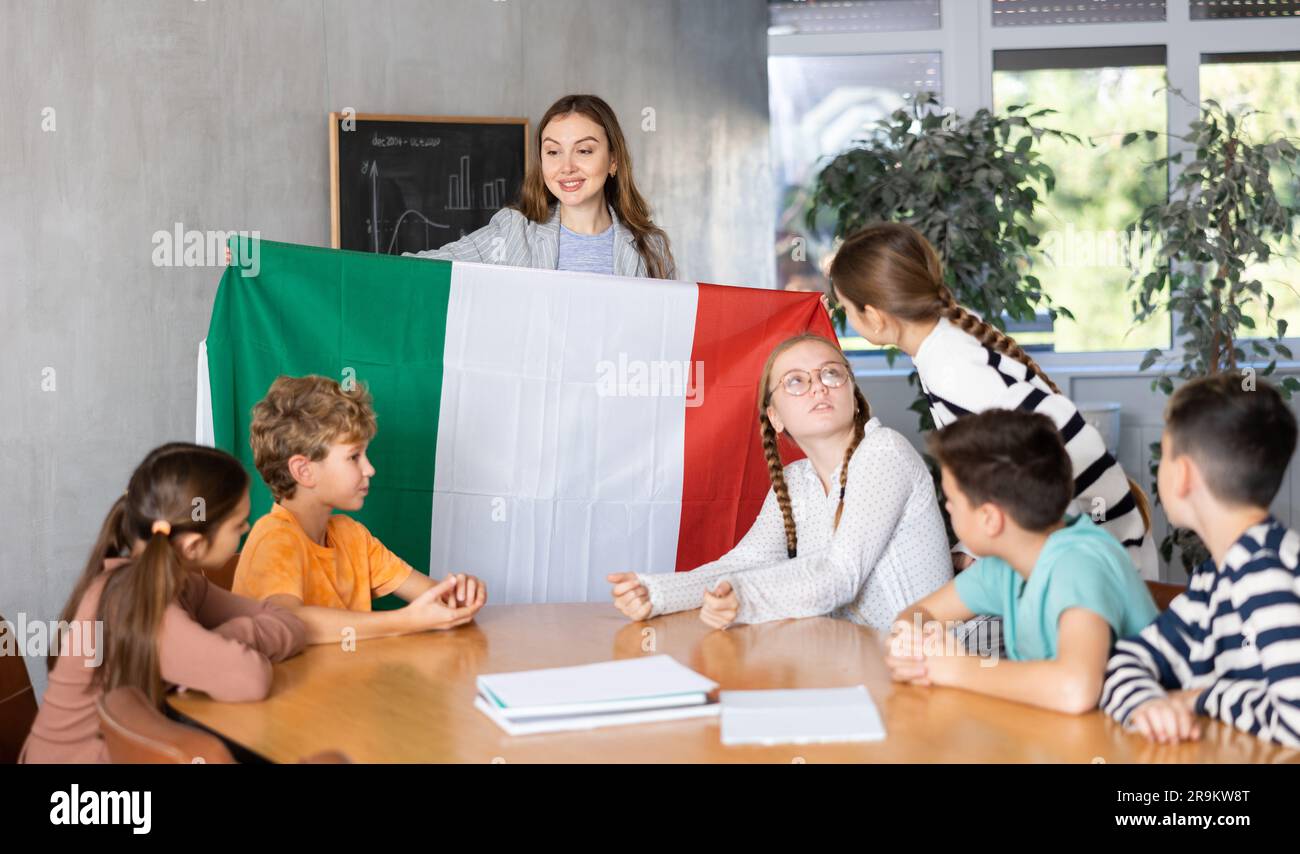 Teacher holds the flag of Italy in her hands and tells the students ...