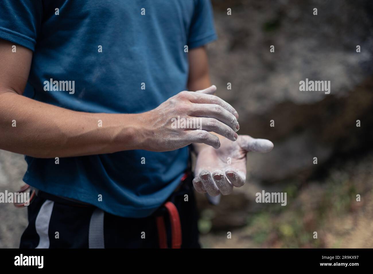 An extreme climber wearing climbing gear is wiping their hands on the ...