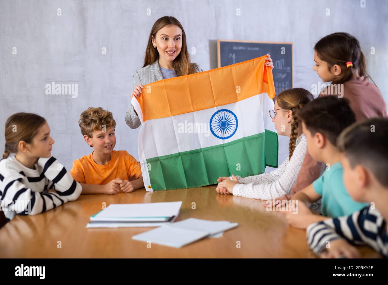 Female teacher working with students in school class, talking about ...