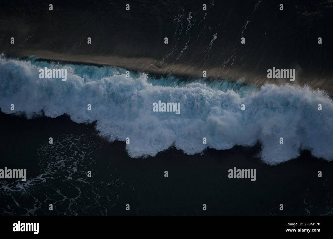Aerial top down drone view of a clear blue water wave breaking near ...