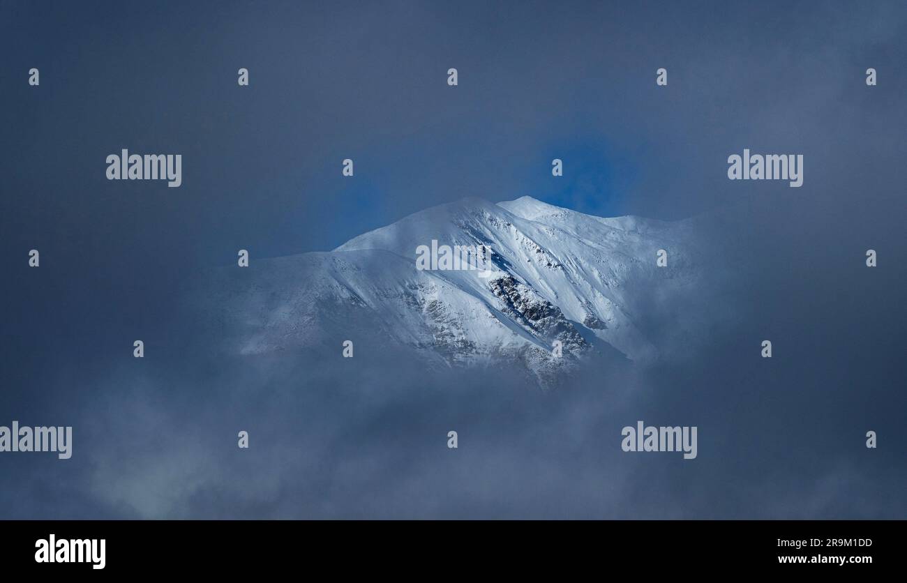 White snow capped mountain ridge peak summit with clear blue sky ...