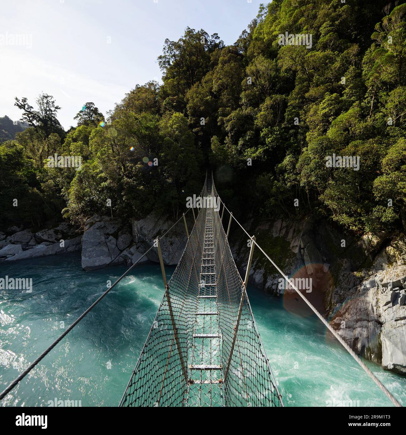 Cesspool Gorge hanging metal swing bridge leading over turquoise ...