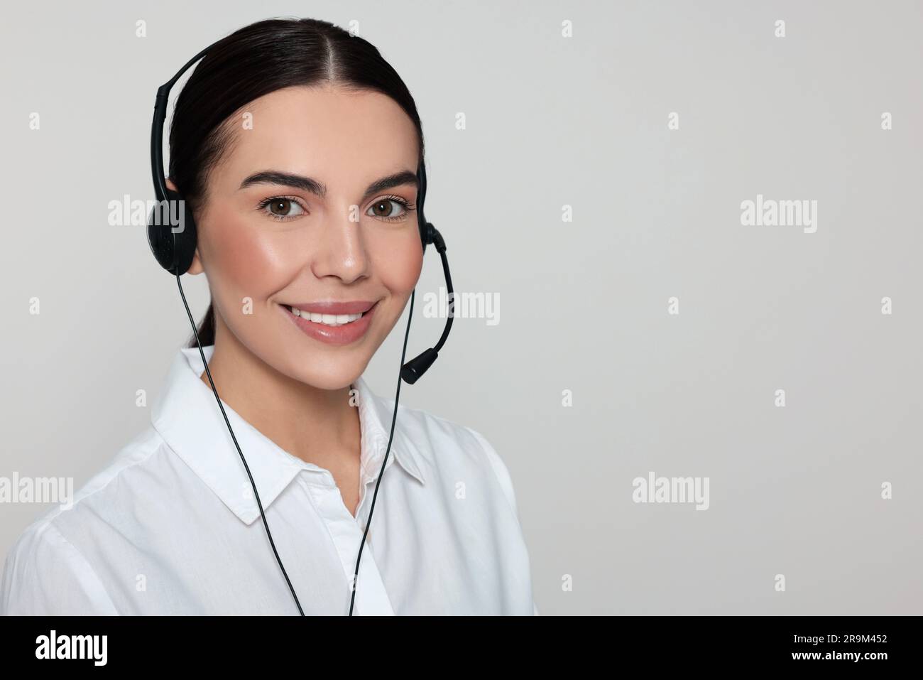Hotline operator with modern headset on light grey background, space ...