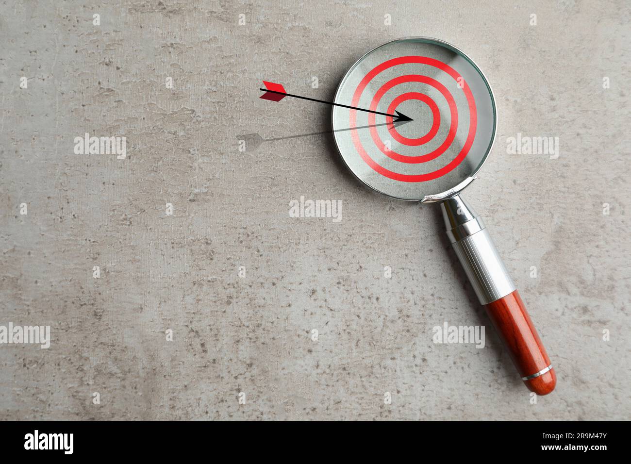 Magnifying glass with illustration of target and arrow on grey textured ...