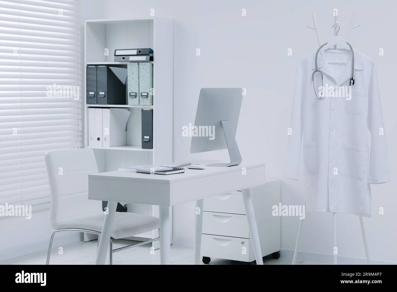 White doctor's gown and stethoscope hanging on rack in clinic Stock ...