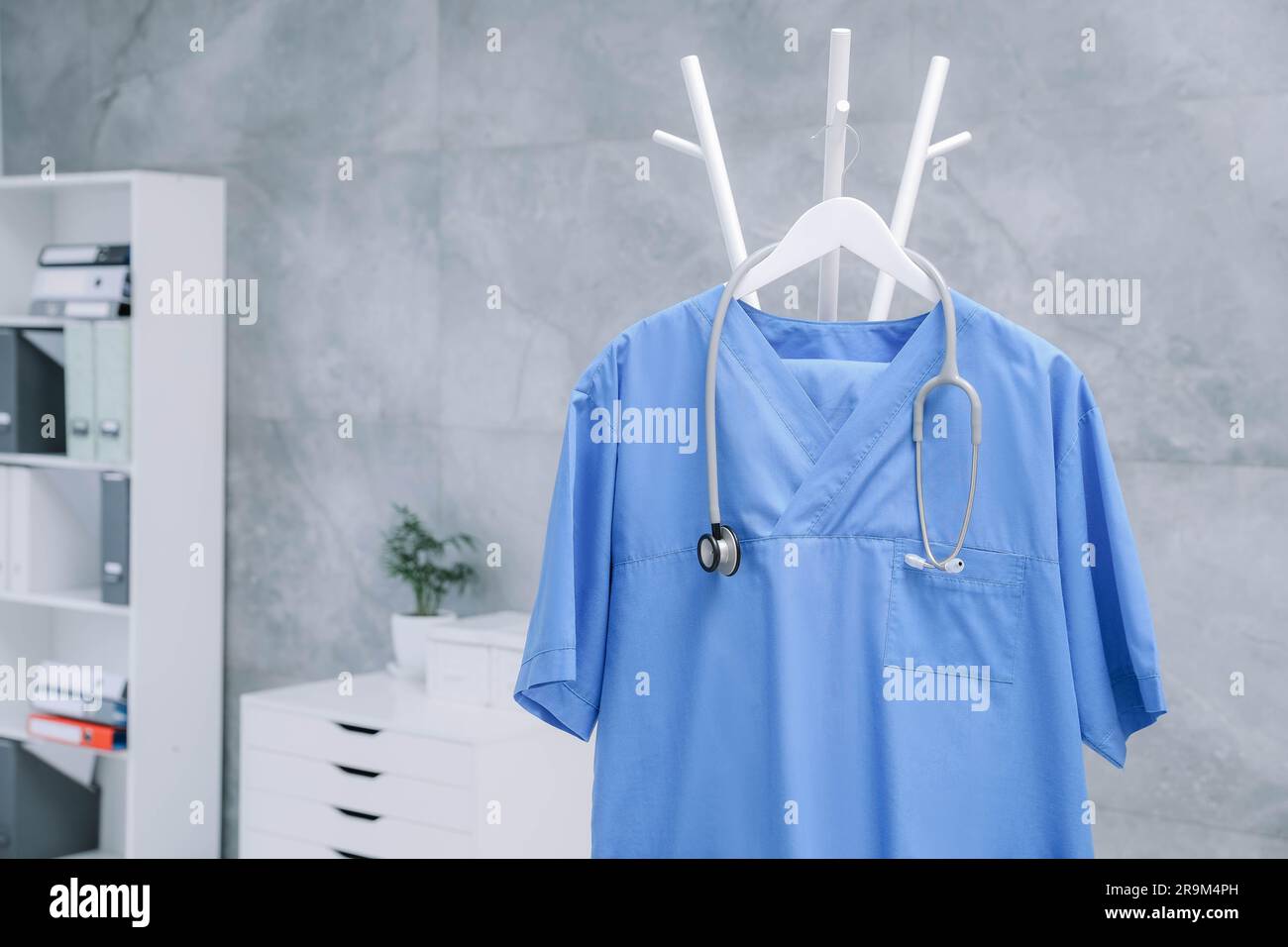 Blue medical uniform and stethoscope hanging on rack in clinic. Space ...