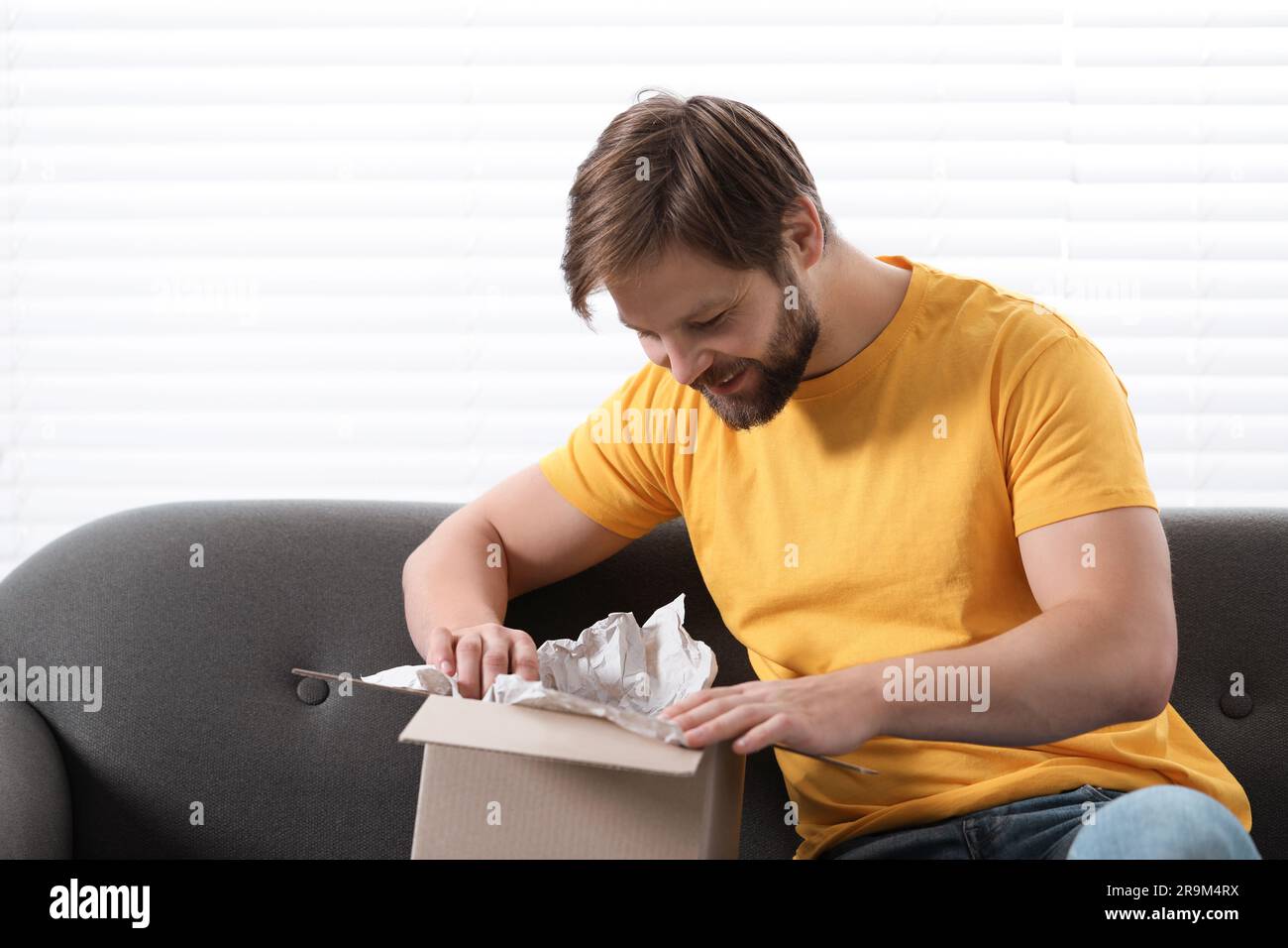 Happy man opening parcel at home. Internet shopping Stock Photo - Alamy