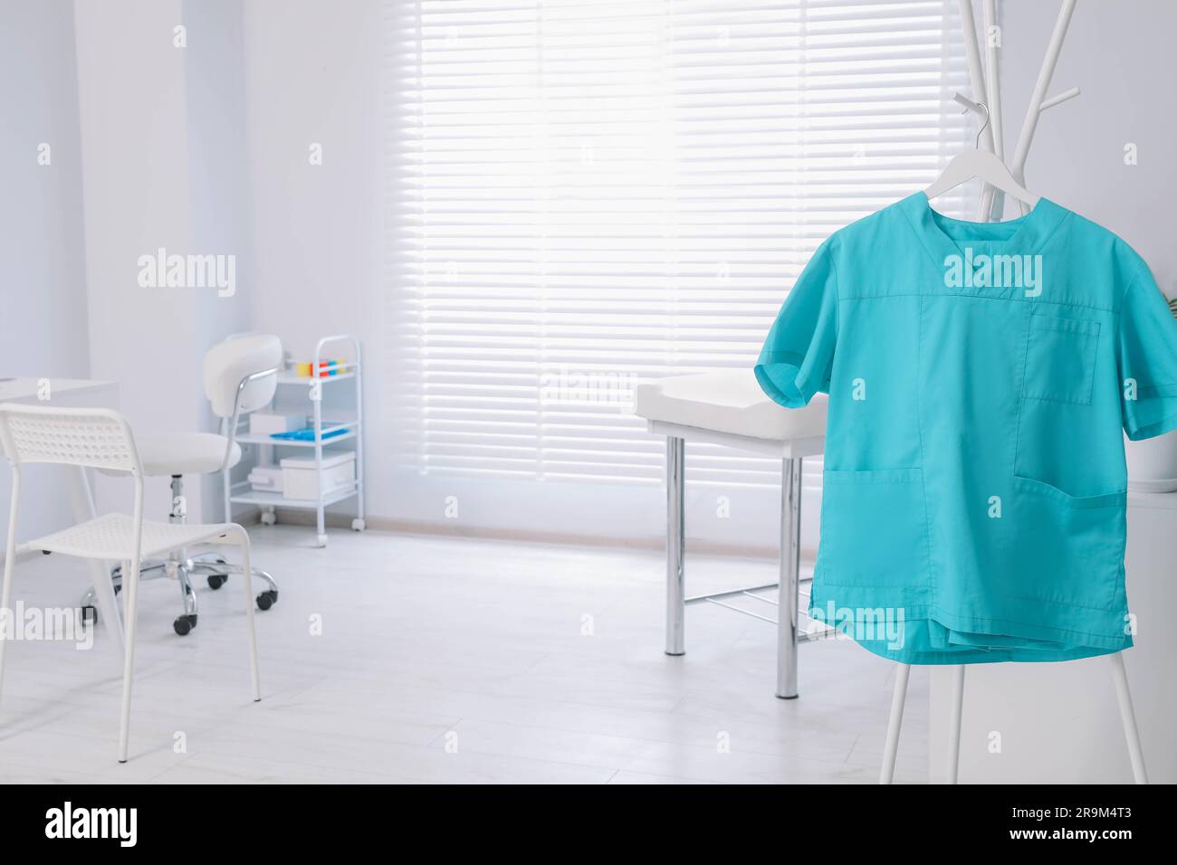 Turquoise medical uniform on rack in clinic. Space for text Stock Photo ...