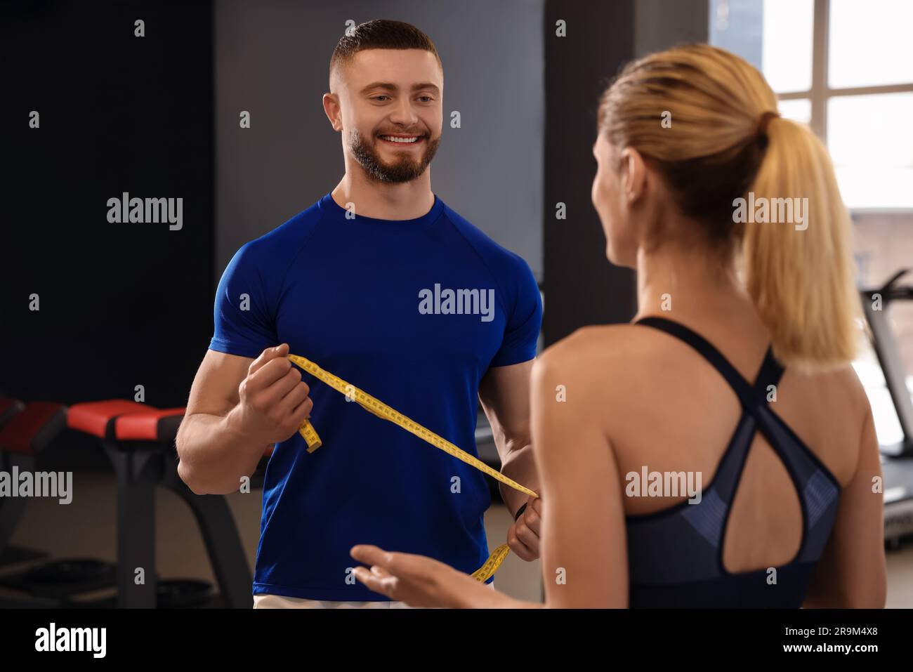 Trainer having discussion with woman in gym Stock Photo - Alamy