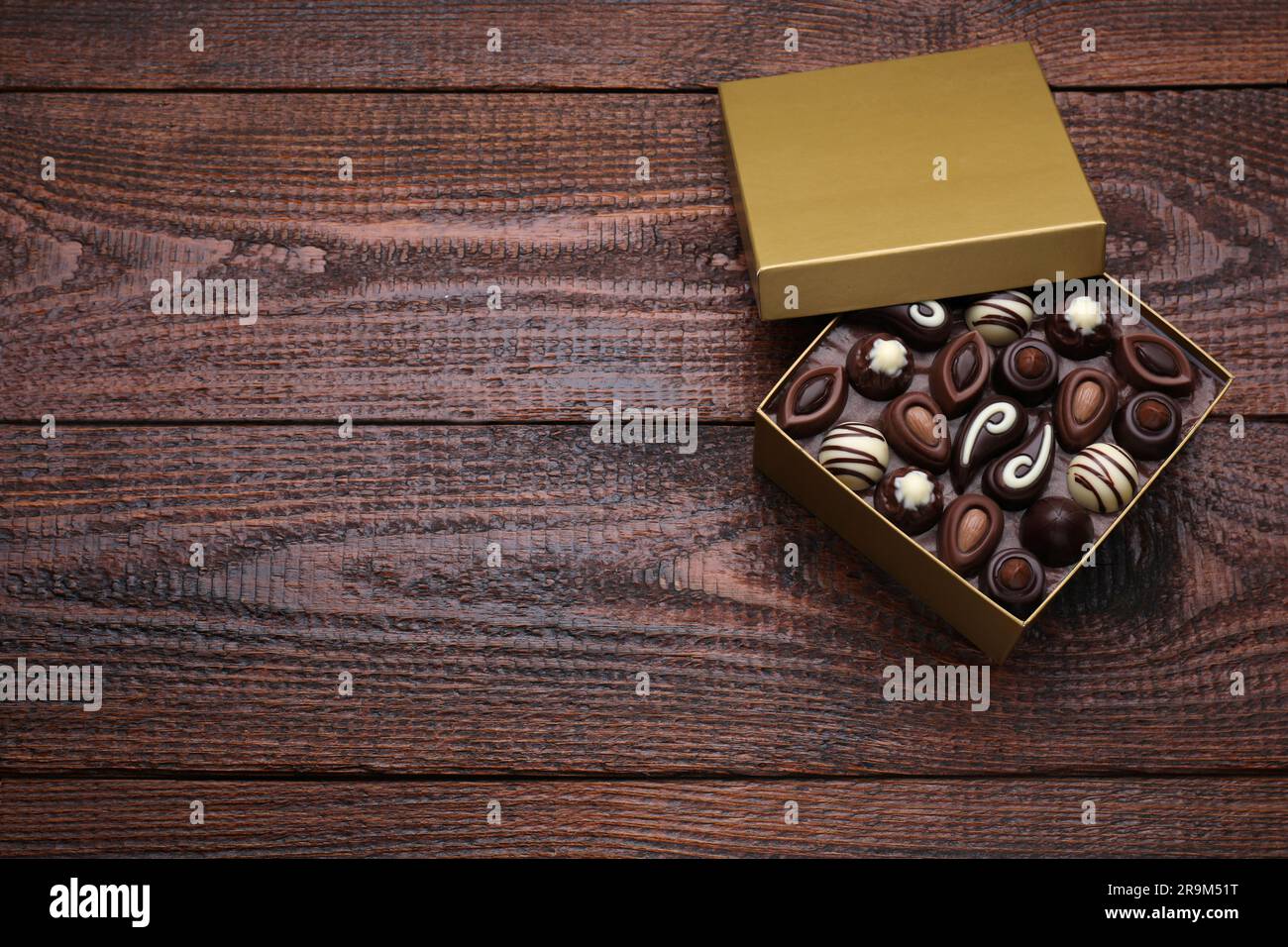 Open box of delicious chocolate candies on wooden table, top view ...