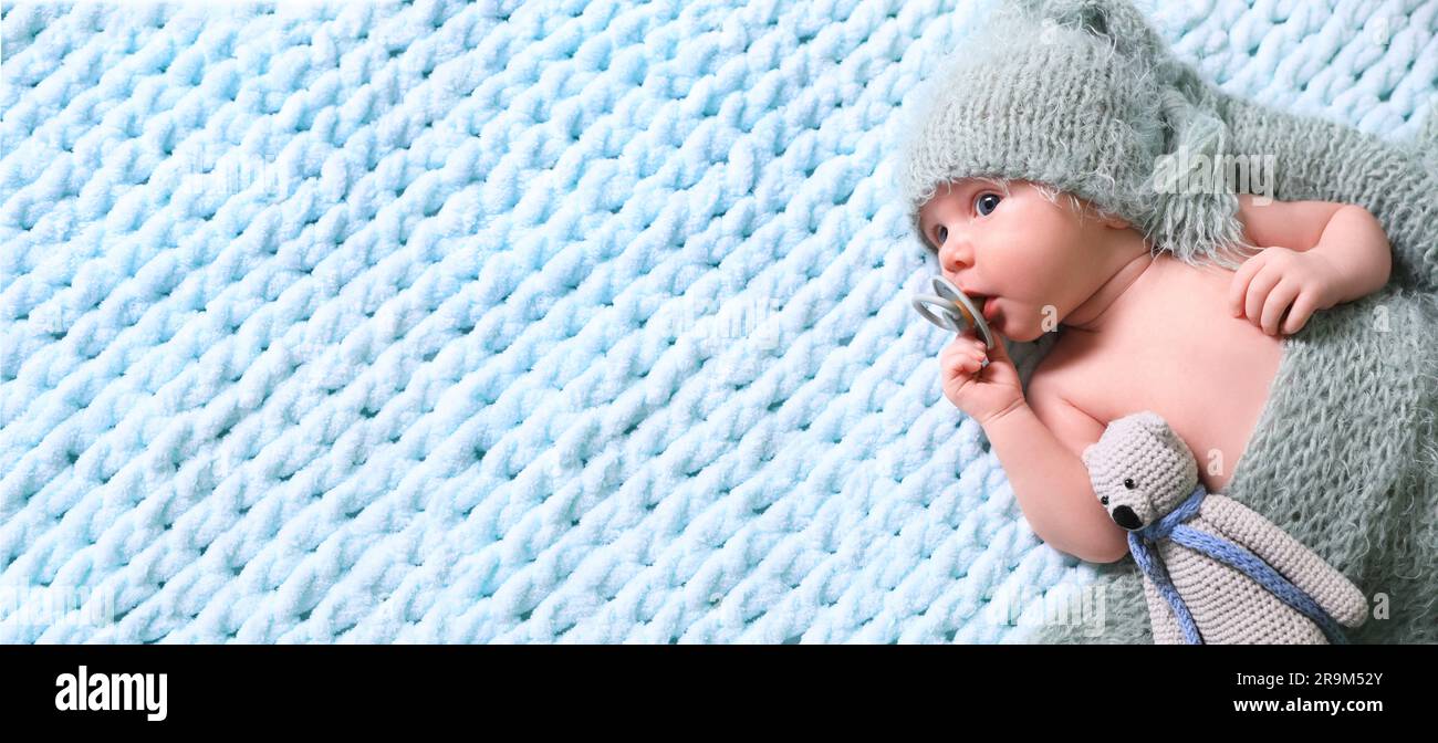 Cute baby baby with pacifier and crochet toy on light blue blanket, top ...