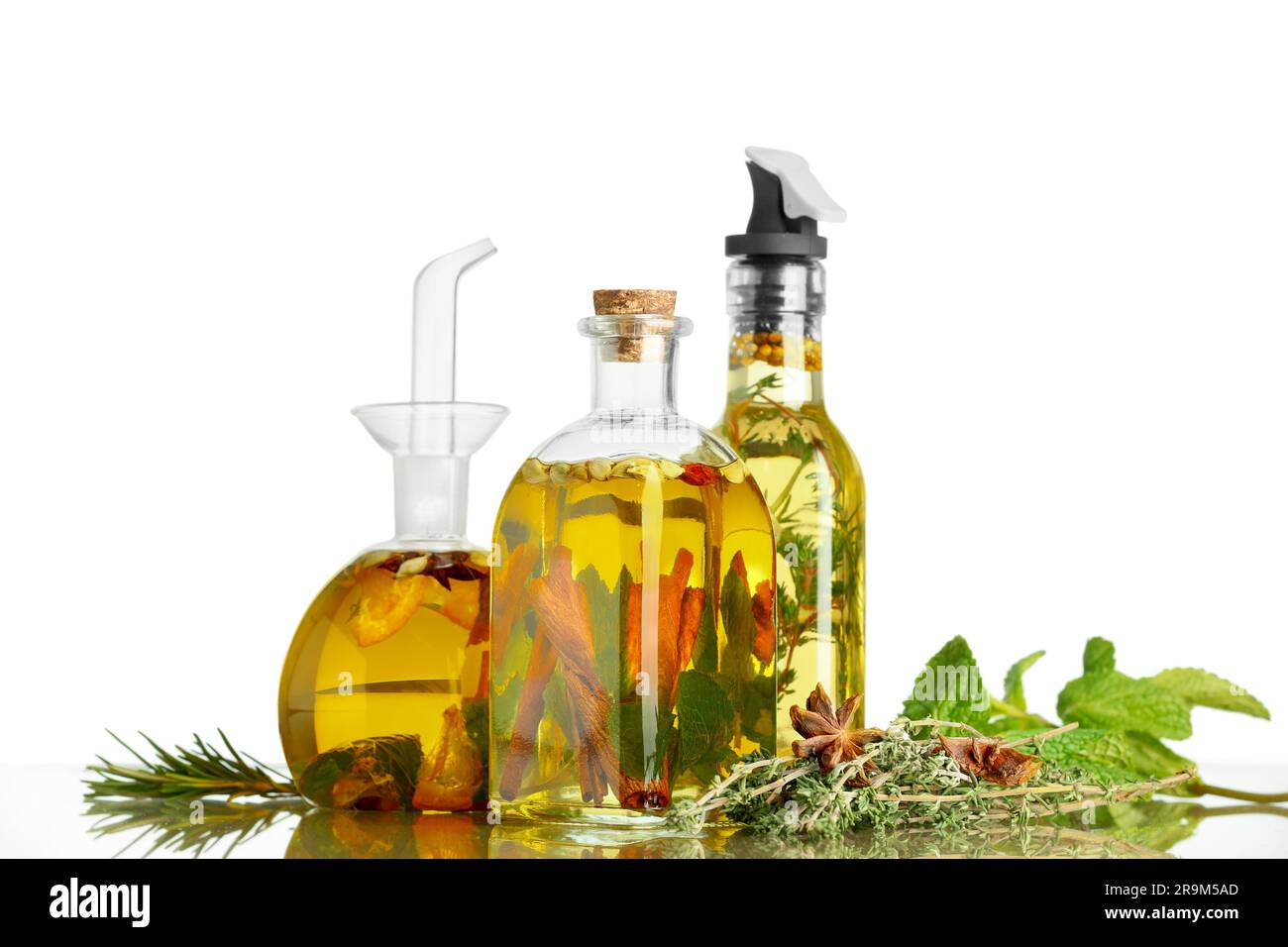 Cooking oil with different spices and herbs in bottles on light table ...