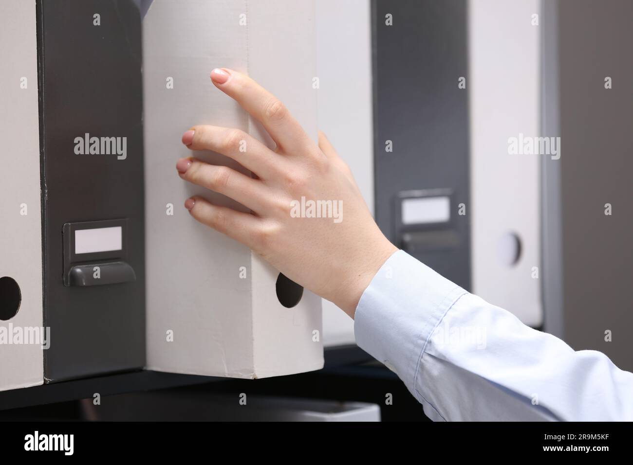 Woman taking folder with documents from shelf in office, closeup Stock ...