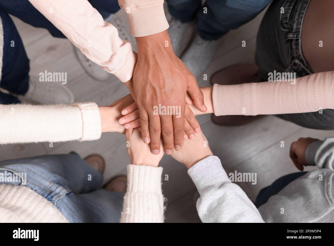 Group of multiracial people joining hands together indoors, top view ...