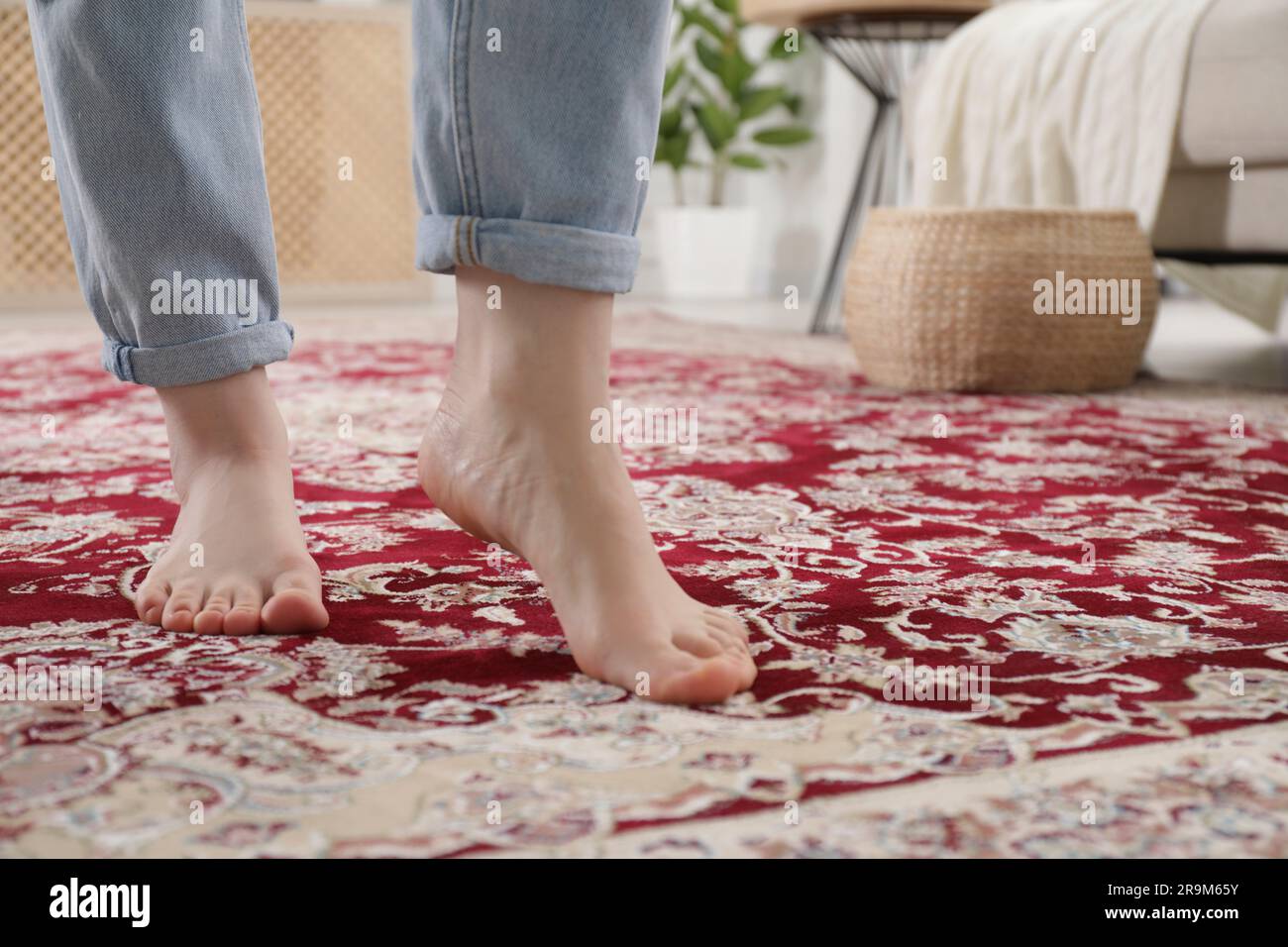 Woman standing on carpet with pattern at home, closeup. Space for text ...