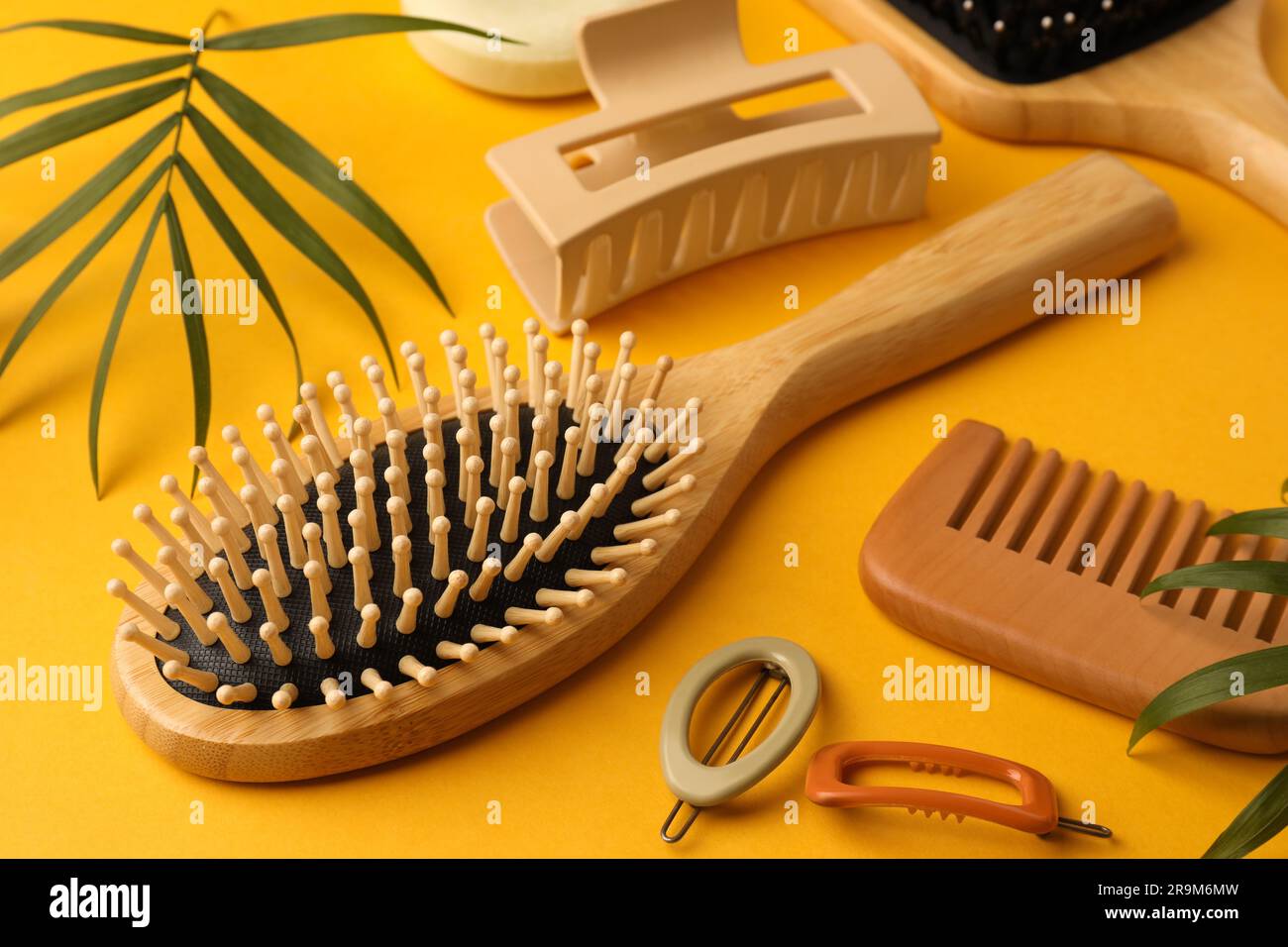 Wooden brushes, comb and different hair products on orange background ...