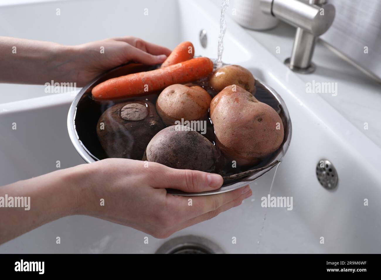 Woman washing fresh vegetables in kitchen sink, closeup. Cooking ...