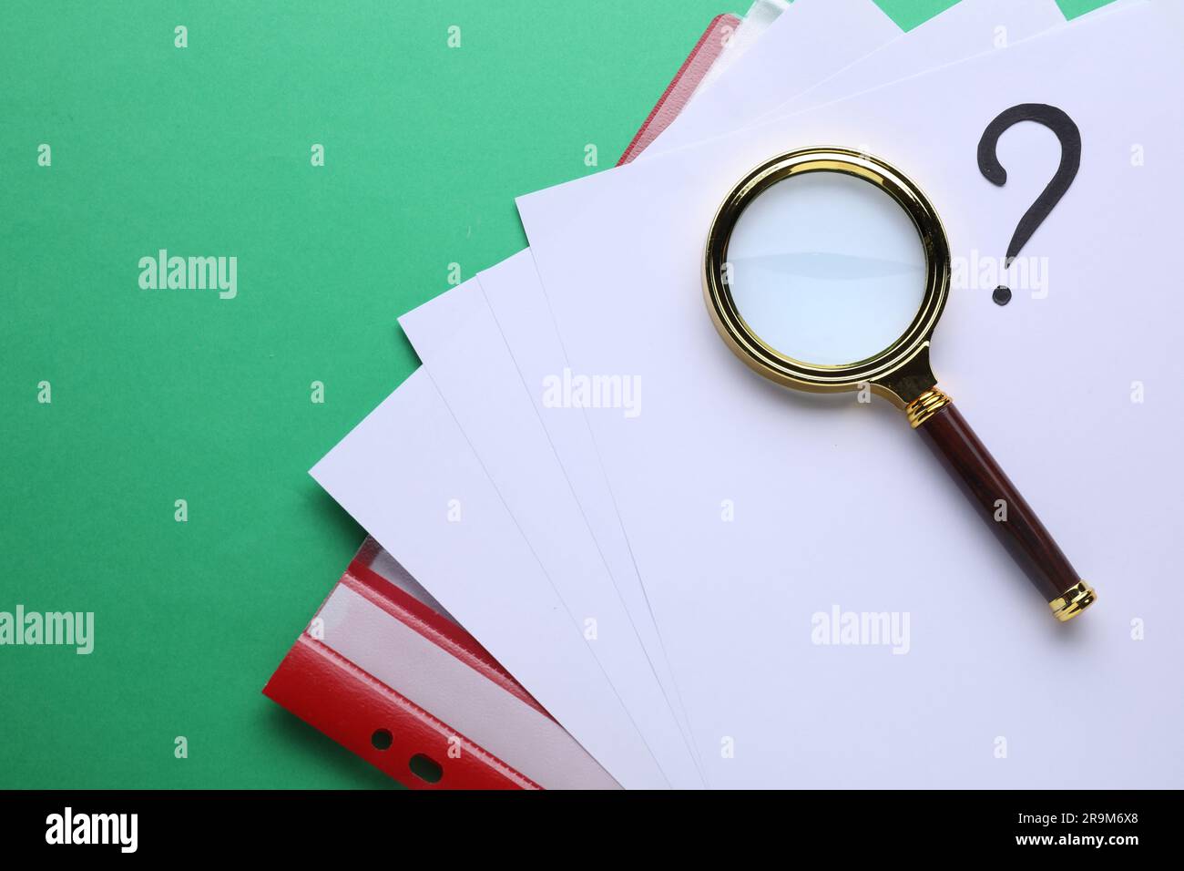 Magnifying glass, folder with paper sheets and question mark on green ...