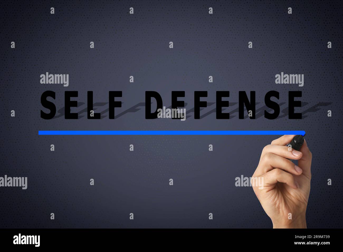 Man underlining words Self Defense with marker glass board against dark ...