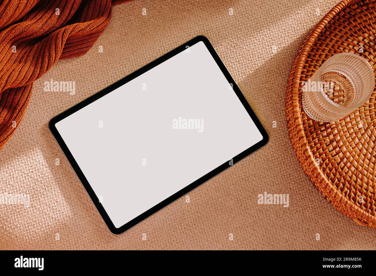 Tablet with blank screen lying on the light couch surface. Device mock ...