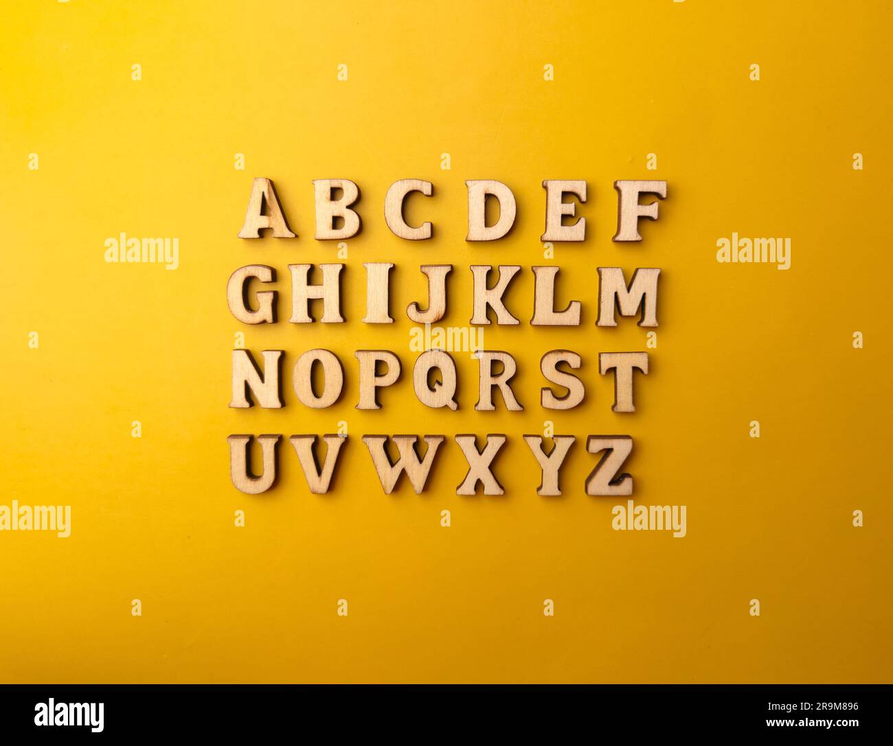 Set of 26 wooden letters,whole alphabet on yellow background, view from ...