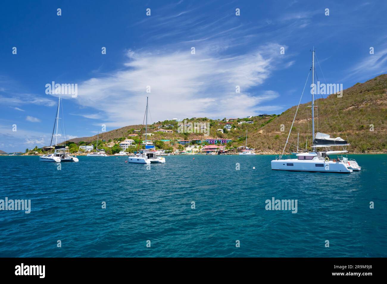 Four catamaran sailboats are moored in the beautiful blue waters off ...