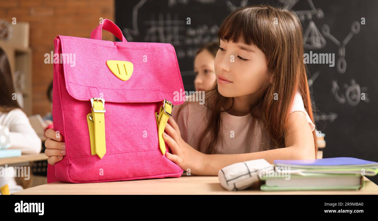 Little girl with backpack sitting at desk in classroom Stock Photo - Alamy